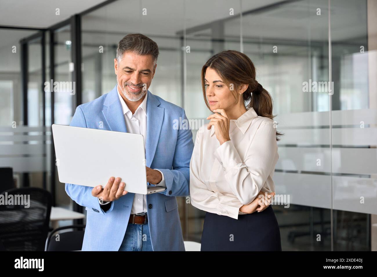 Busy professional team two executives standing in office using laptop ...