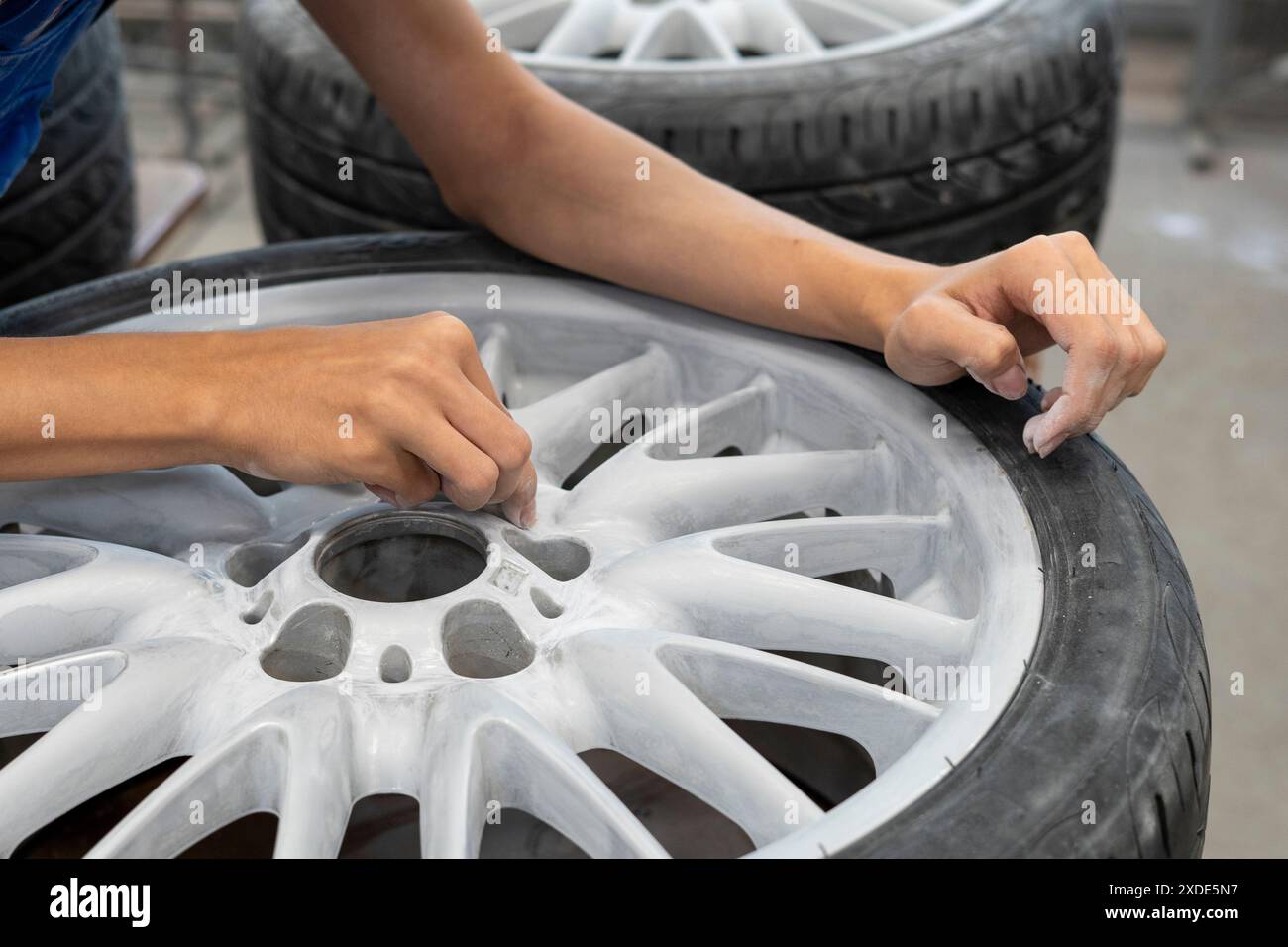 Worker preparing car wheel rims for painting Stock Photo - Alamy