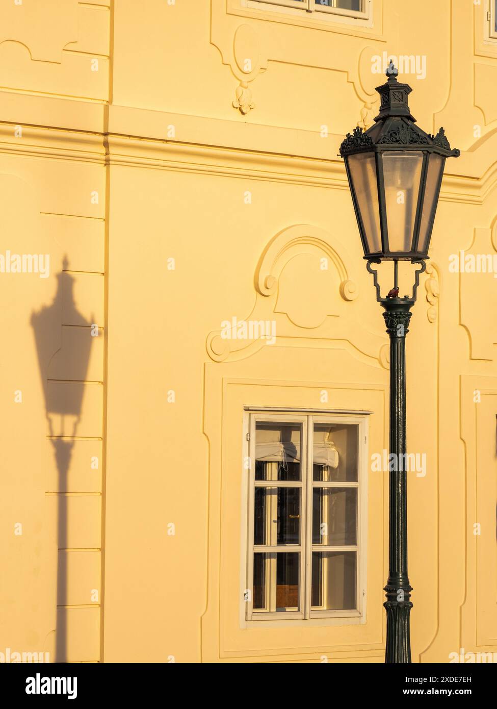 An ancient street lamp and its shadow on the facade of an old house ...