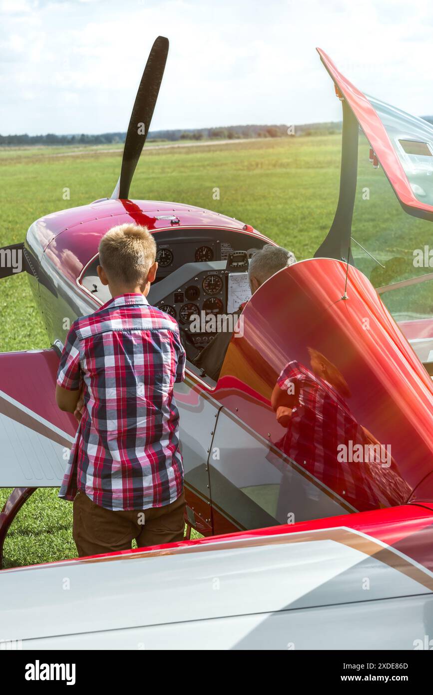 A Young Boy Watching And Learning How To Fly A Red Aerobatic Plane ...