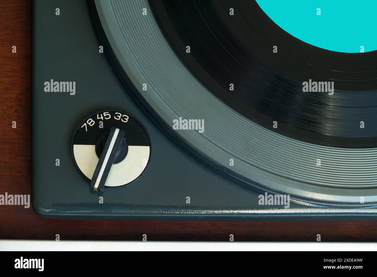 Part of retro record player in wood finish case with speeds selector and 7 inch vinyl record ...