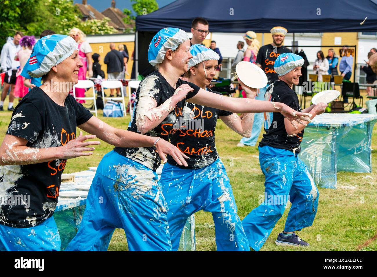 Team of four women, splattered in custard, throwing a volley of pies ...
