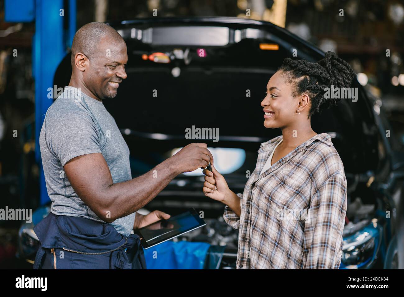 Garage worker return give a car key to customer for vehicle service ...