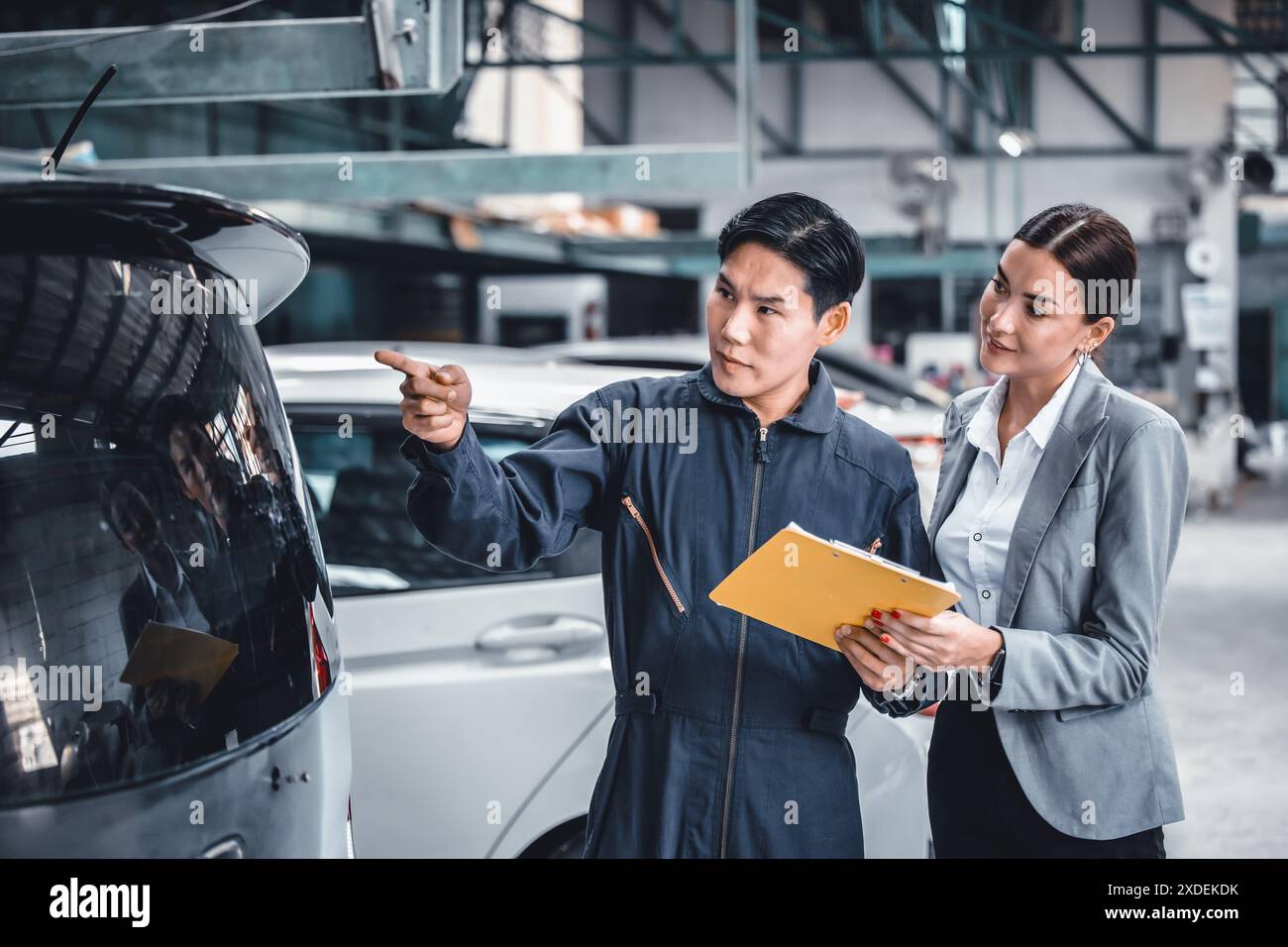 Mechanic working in a car repair shop is estimating the damage and cost ...