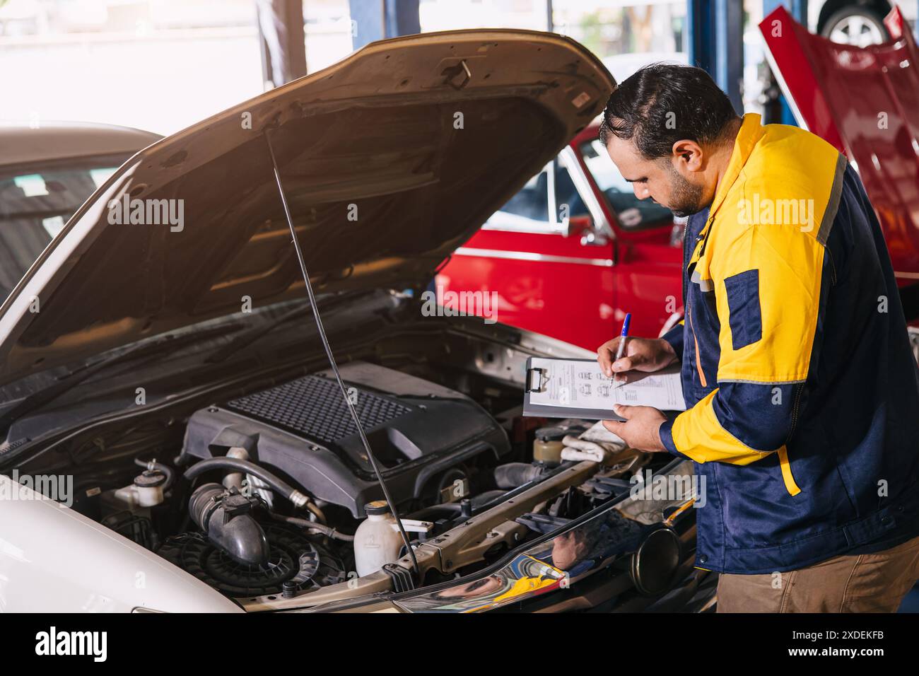 mechanic man checking engine open hood looking check list car ...