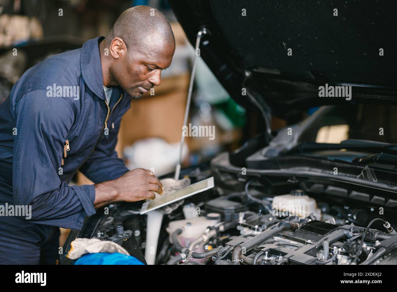 Garage professional working auto service checking engine. Mechanic man using tablet computer ...