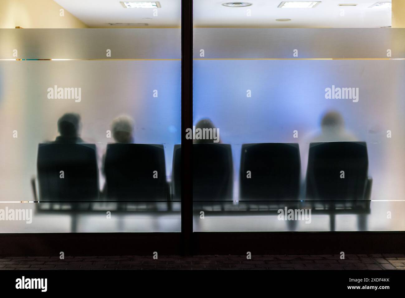 Silhouettes of people sitting in a waiting room with frosted glass ...
