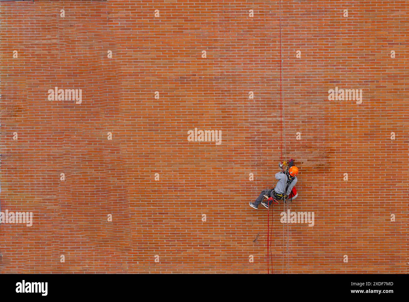 A worker hangs from a façade to carry out cleaning work at height ...