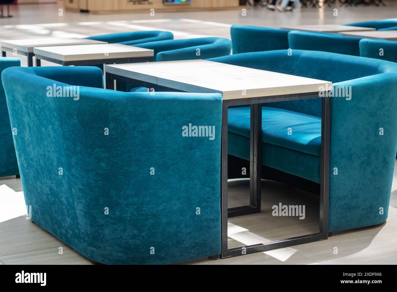 A row of rectangular tables and chairs in azure color arranged in a ...