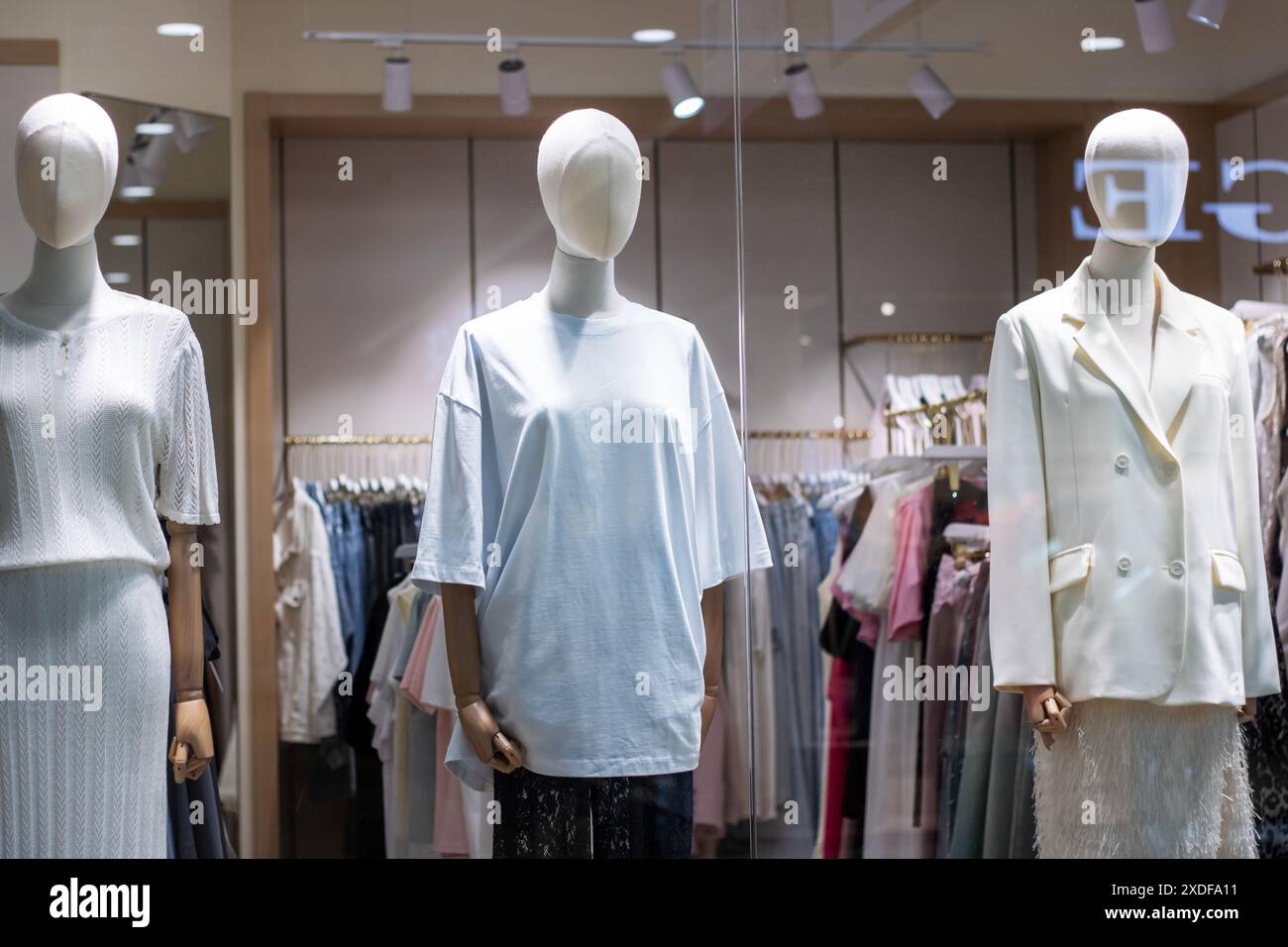 In the store, three mannequins are dressed in white clothes, showcasing ...