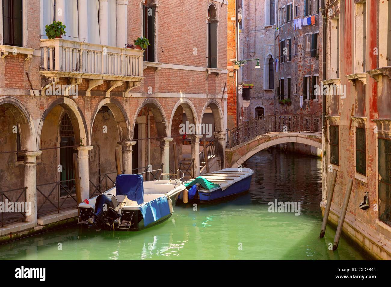 Venetian canal with boats and arched building facade in Venice, Italy ...