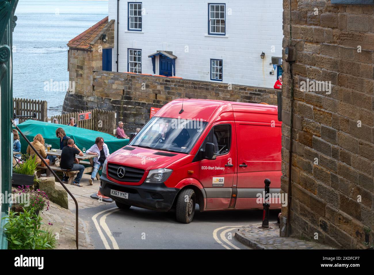 A red Parcelforce van in the narrow streets of Robin Hood's Bay, a ...