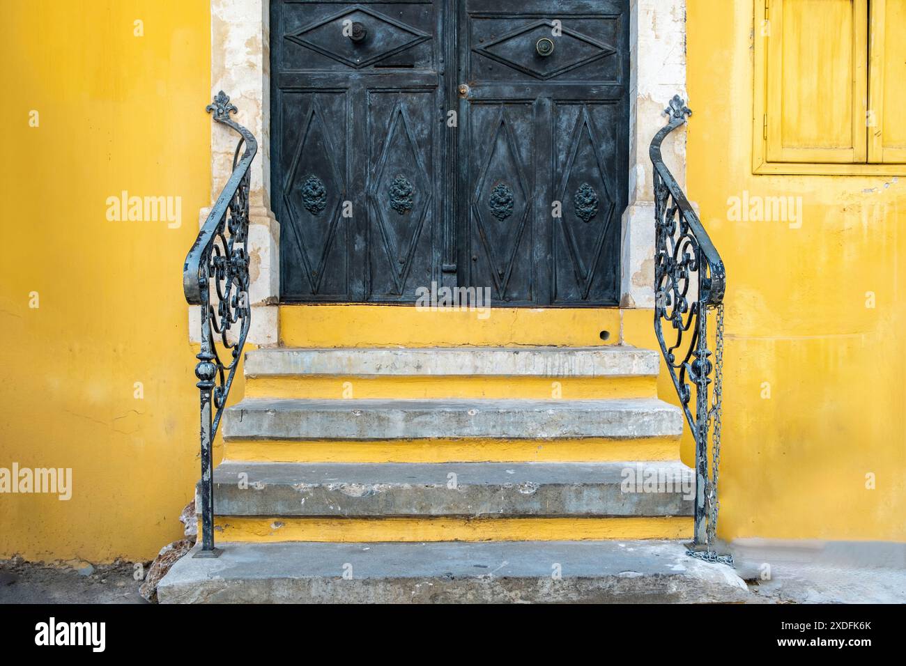 Yellow color building wall and black entrance door, stairs and railing ...