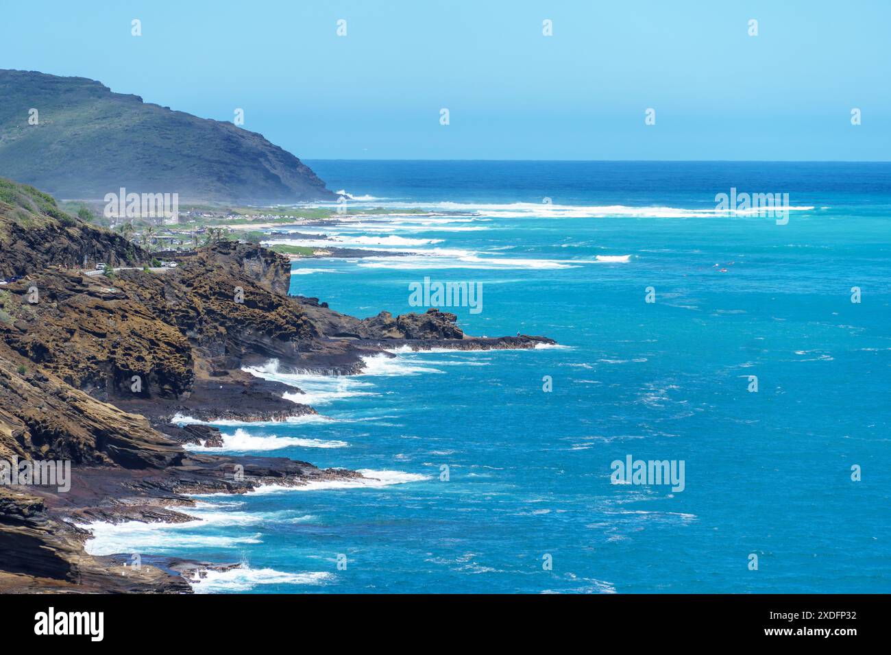 A scenic view of a cliff facing the ocean with waves breaking on the ...
