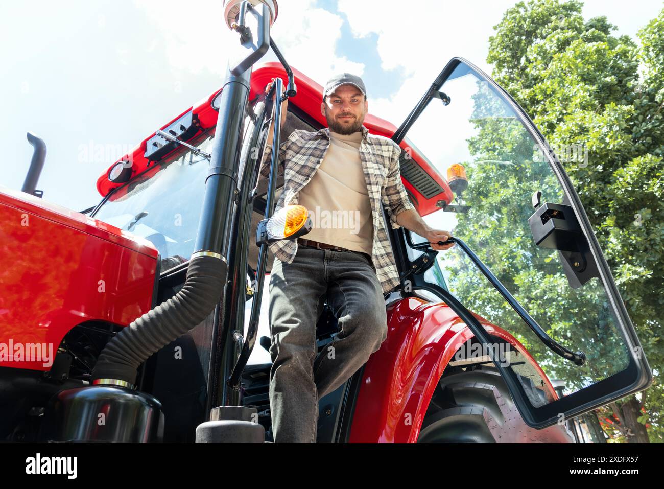 Low angle view portrait of male farm tractor driver on a red tractor in ...