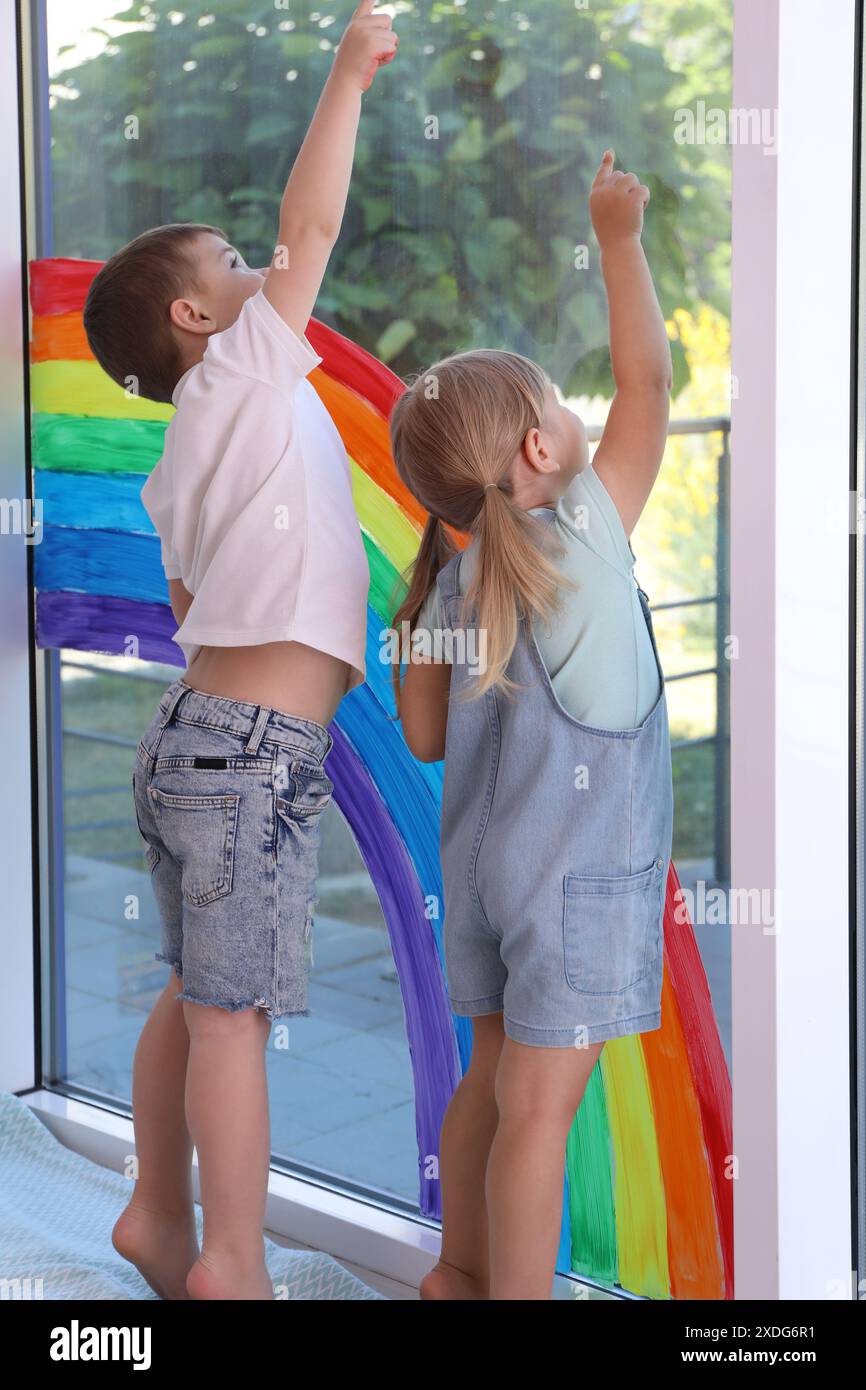 Children touching picture of rainbow on window indoors Stock Photo - Alamy