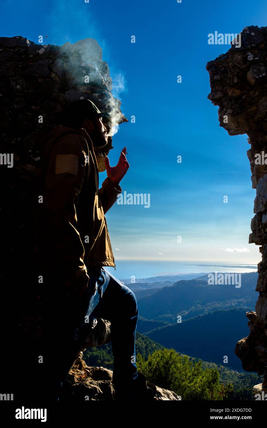 Male model smoking between stone walls blue sky background Stock Photo ...