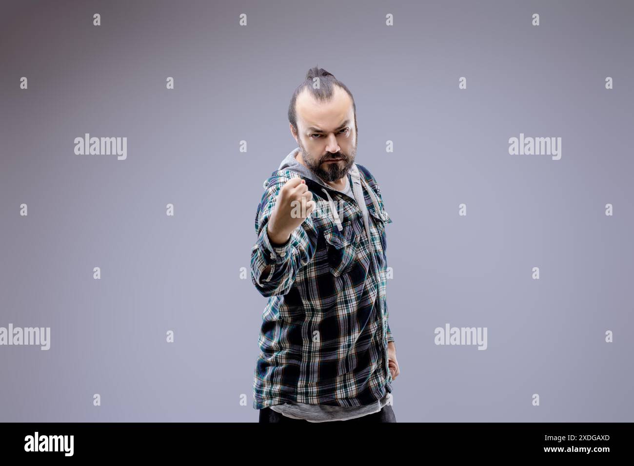 Aggressive man with a beard wearing a plaid shirt is throwing a punch ...