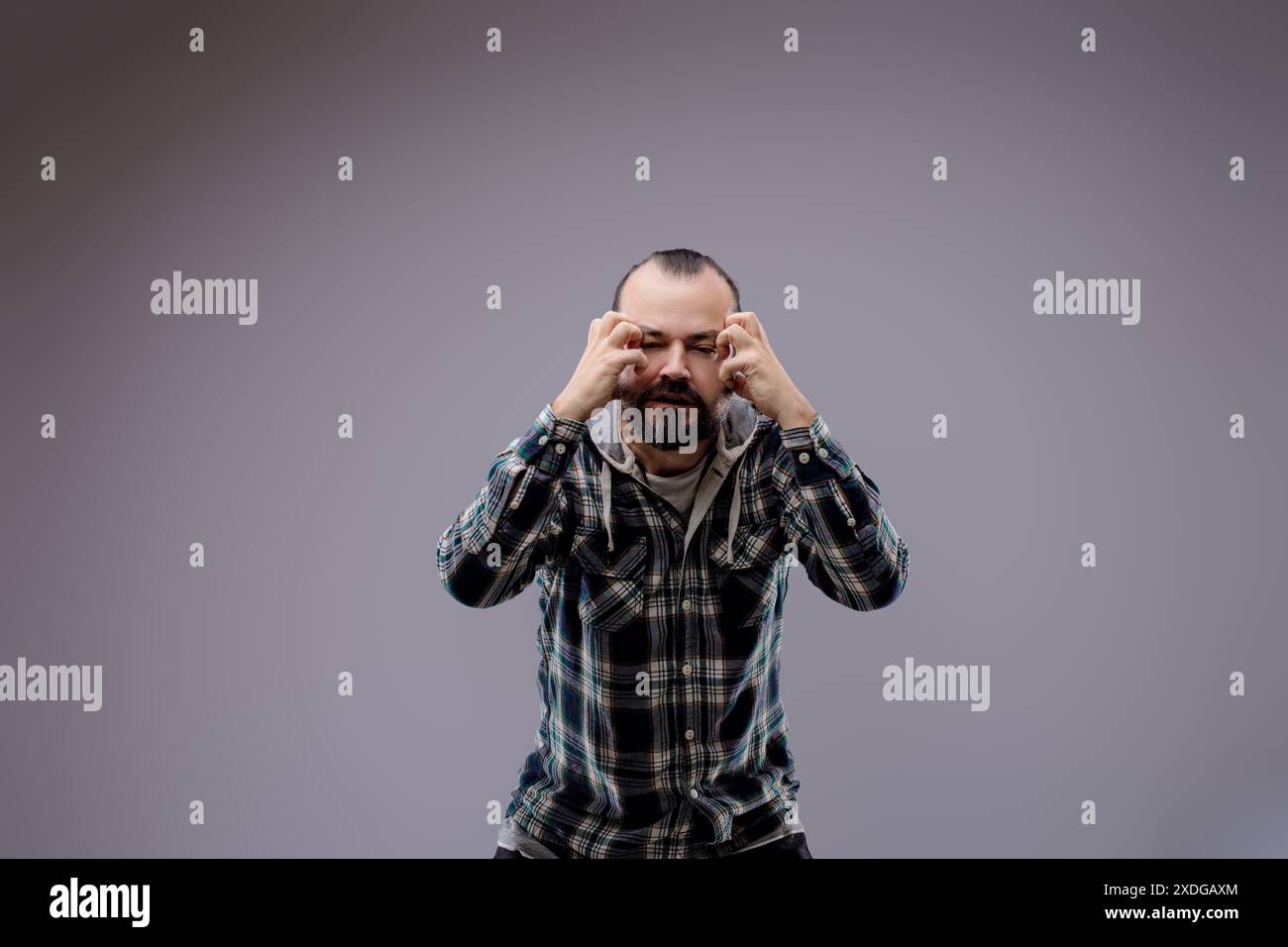 Tired man with a beard rubs his eyes, showing fatigue and frustration ...