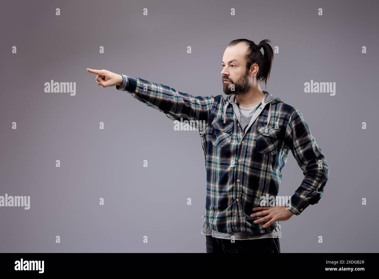 Bearded man pointing accusingly, hand on hip, with a serious expression ...