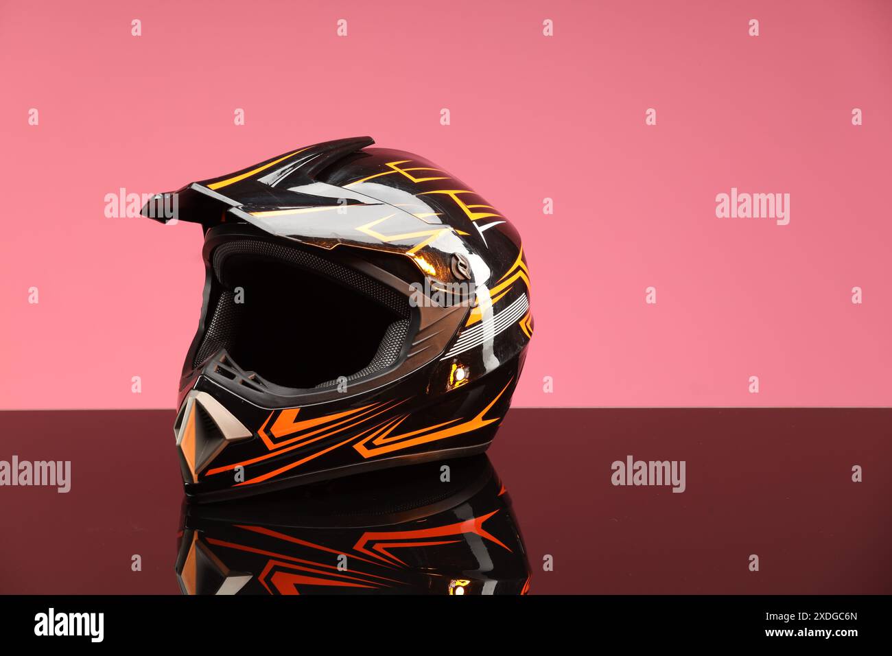 Modern motorcycle helmet with visor on mirror surface against pink ...