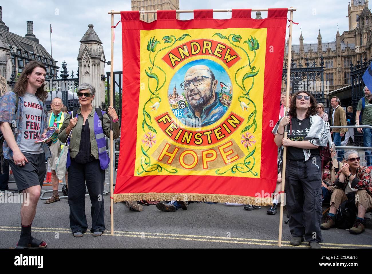London, UK. 22nd June, 2024. Protesters hold a banner with a portrait ...