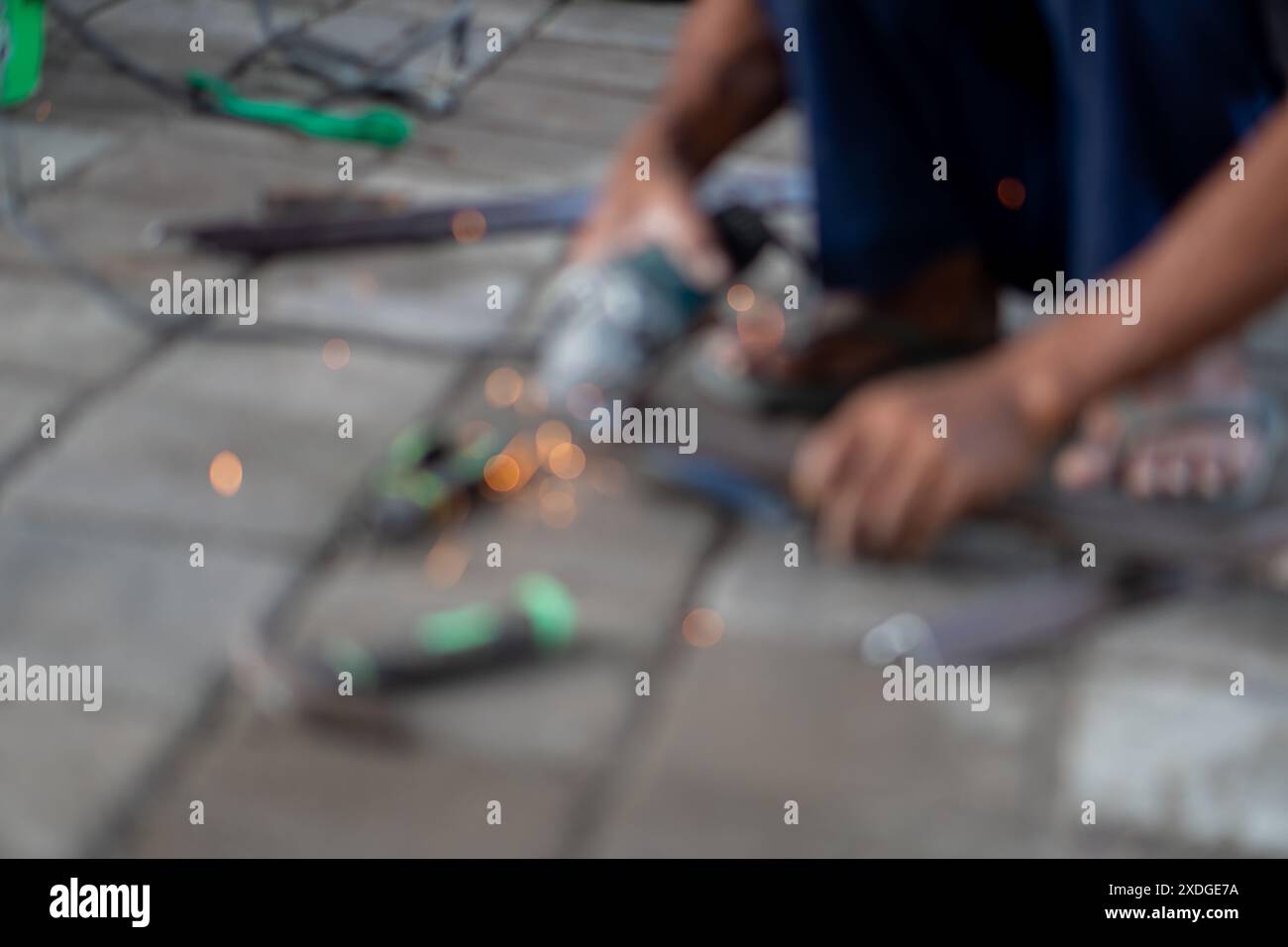 A blurred image of a person using a power tool, with sparks flying ...