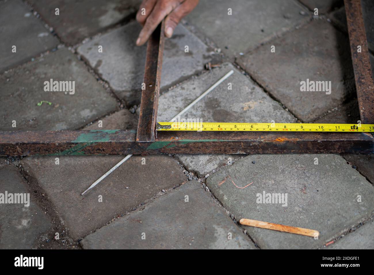 A person measuring a metal frame with a yellow measuring tape on a ...