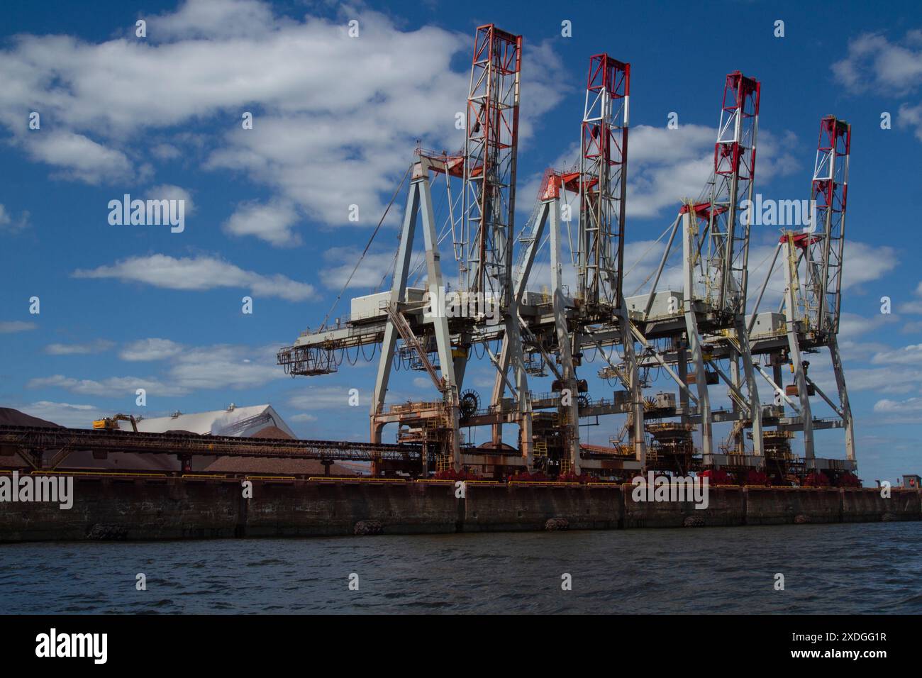 Tall container port cranes wait to transport goods to and from large shipping vessels at the ...
