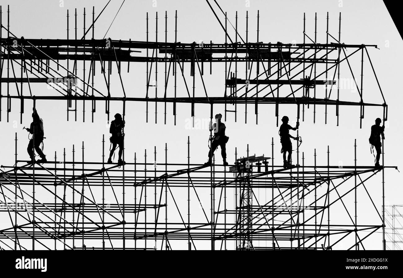 Silhouette of construction workers using teamwork and skill to piece ...