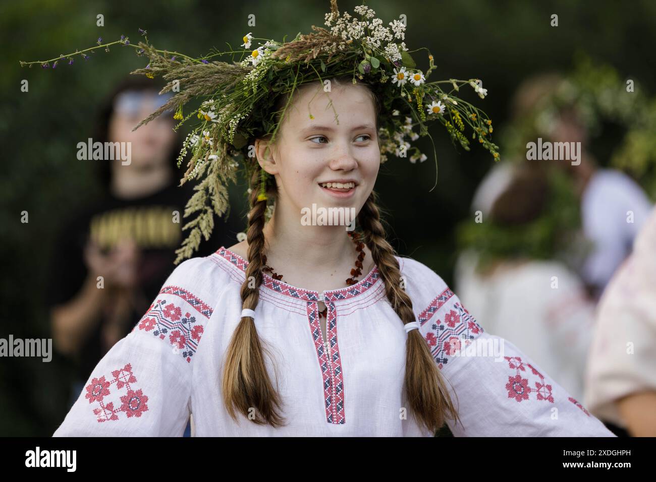 A young woman in a wreath participates in a group dance during the ...