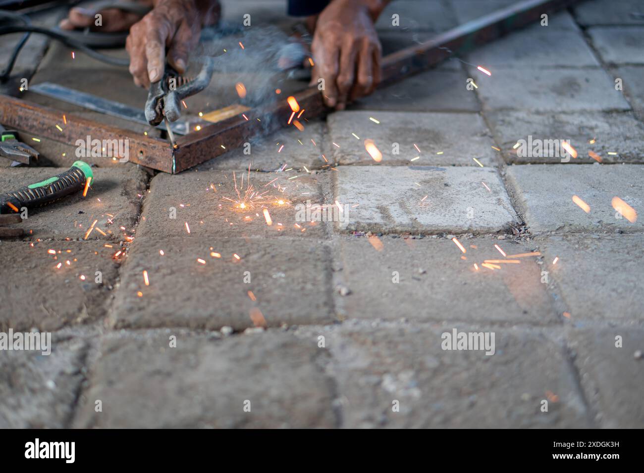 A person measuring a metal frame with a ruler on a paved surface. The ...