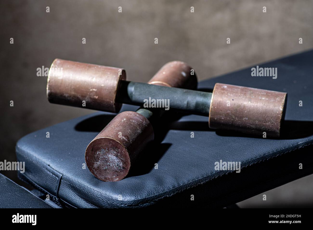A closeup shot of a pair of old-fashioned metal dumbbells resting on a ...