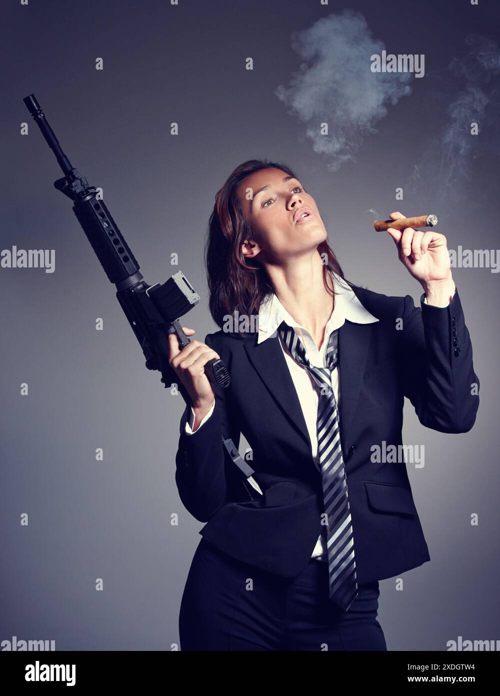 Business woman, cigar and gun in suit on studio background for company ...