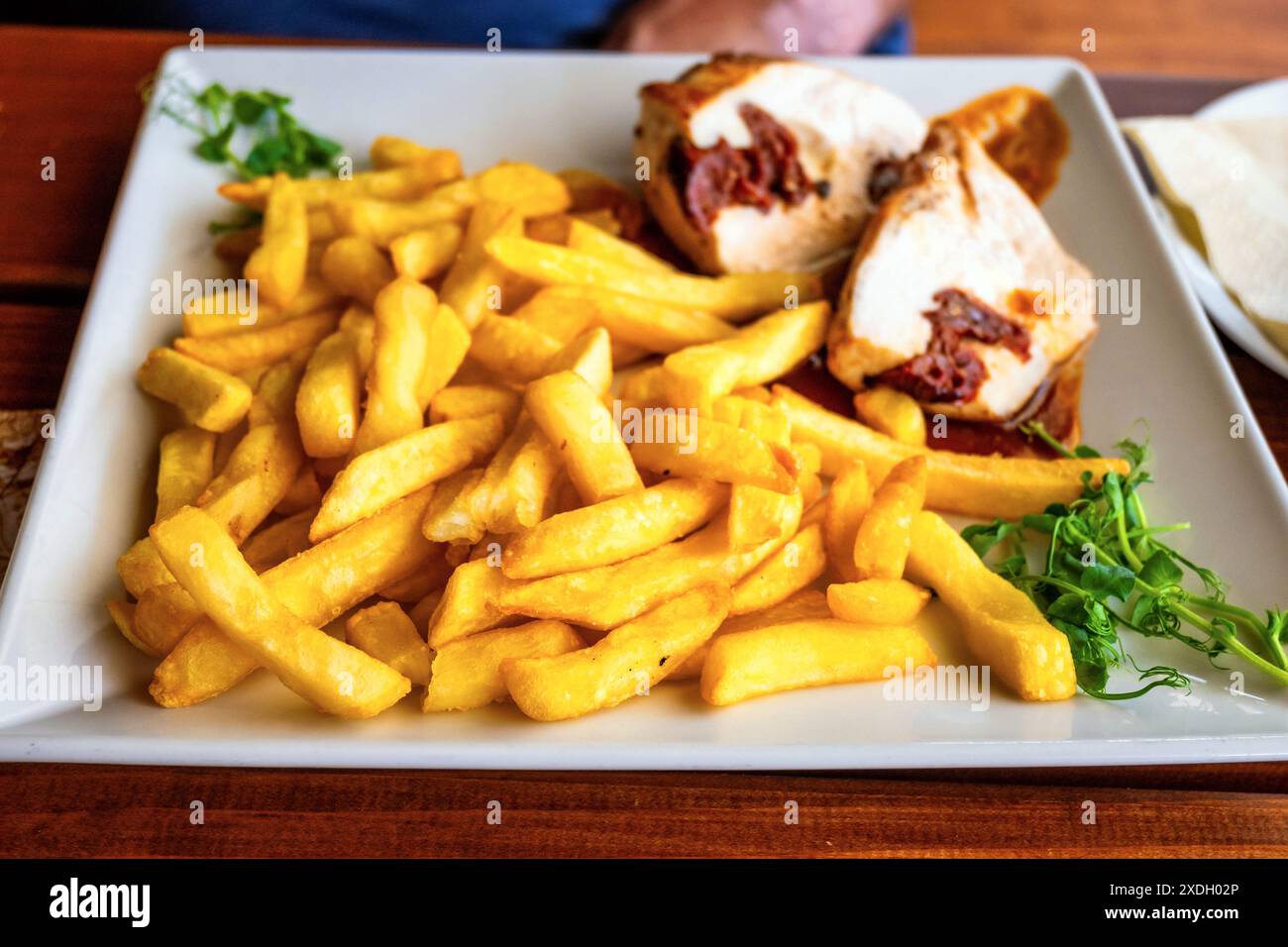 French fries with chicken roulade with dried tomato, sprouted pea leaf ...