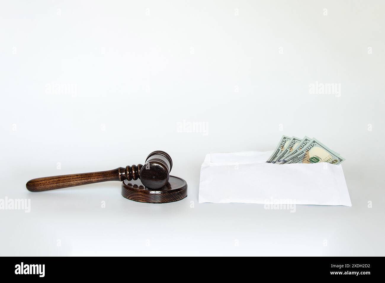 Judge's gavel and dollars in an envelope on a white background ...