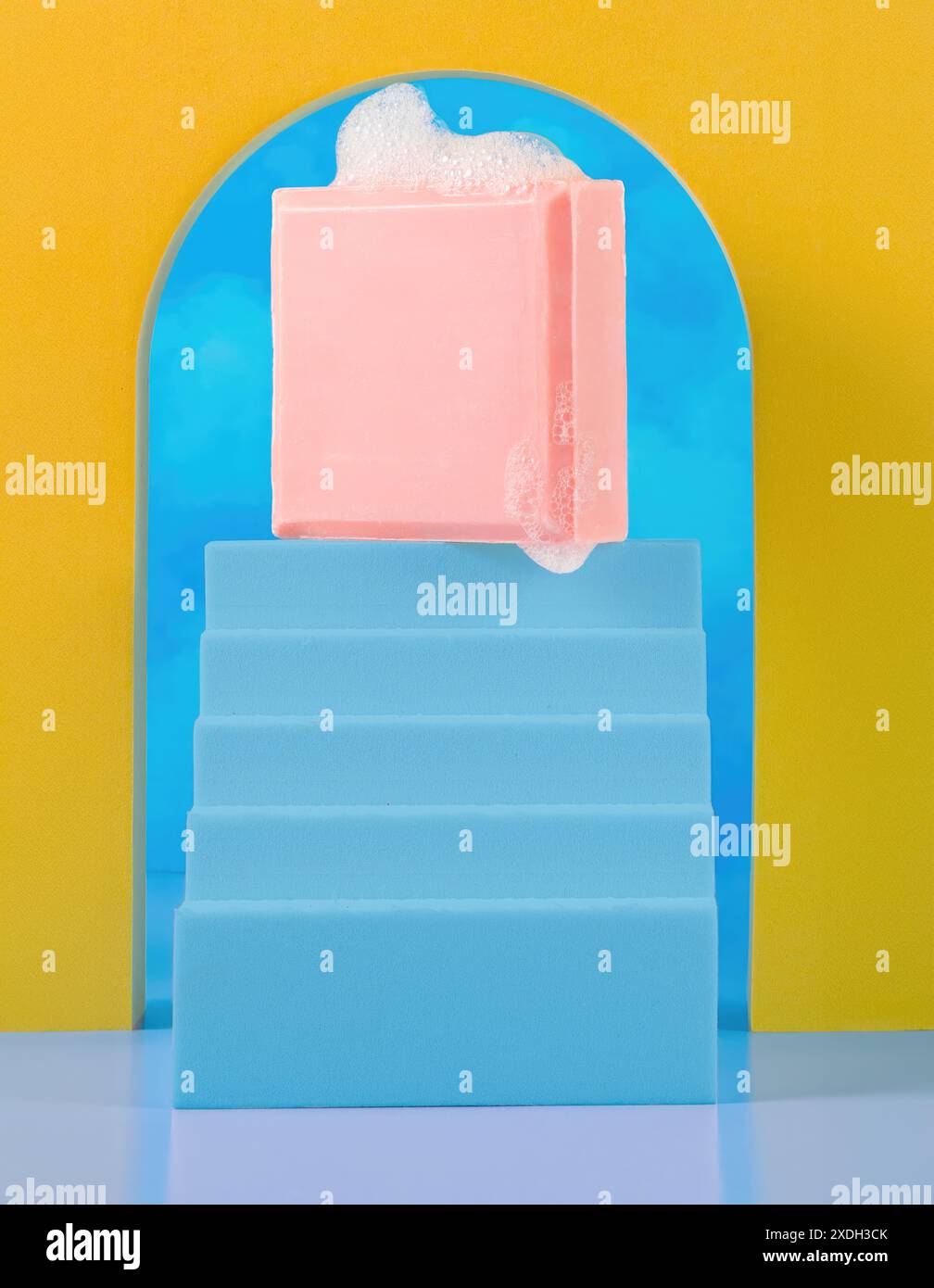 Trendy pink soap bar on foam blue steps, yellow archway, sky backdrop ...