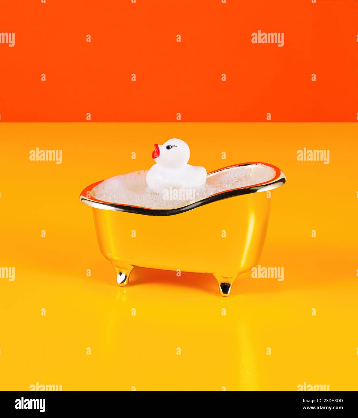 White rubber duck with red beak in a gold bathtub filled with bubbles ...