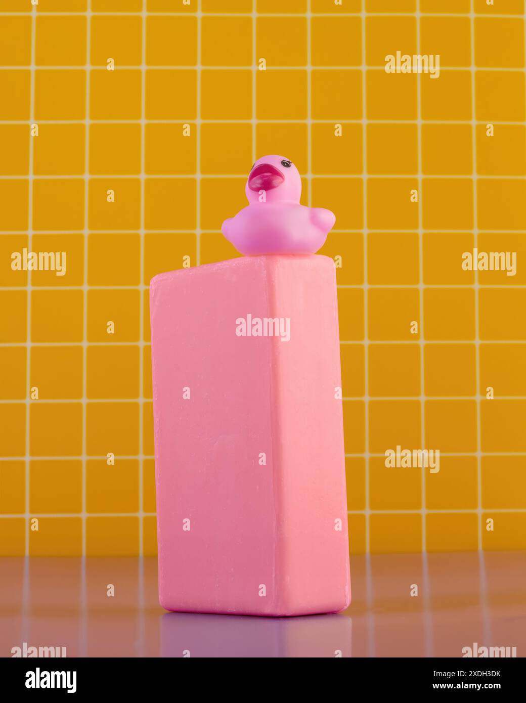 Pink rubber ducky sitting on a tall pink soap bar, vibrant yellow tiled ...