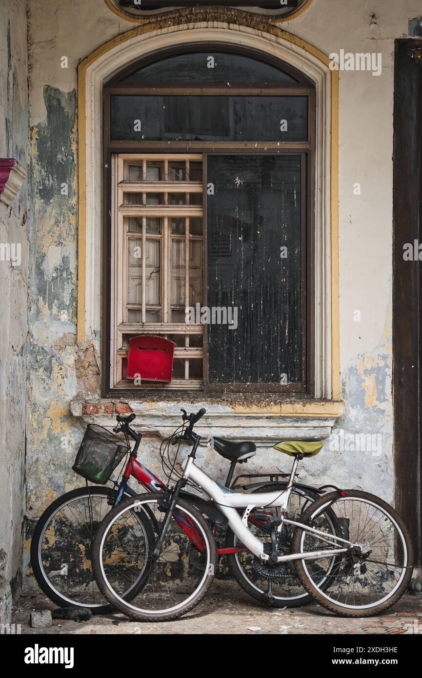 Old rusty bicycles under the window of an abandoned colonial style ...