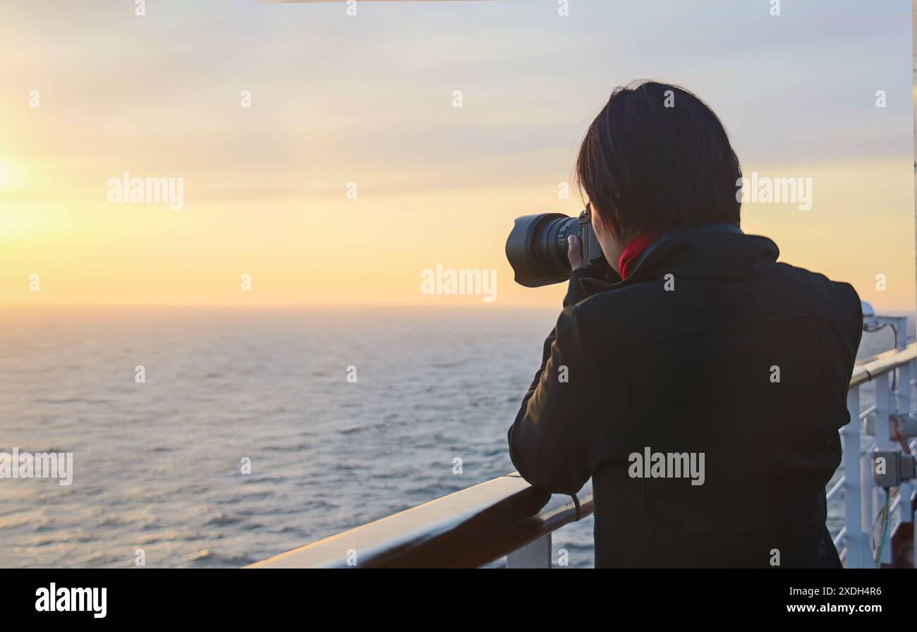 Female photographer taking photos on a cruise ship at sunset. Alaska ...
