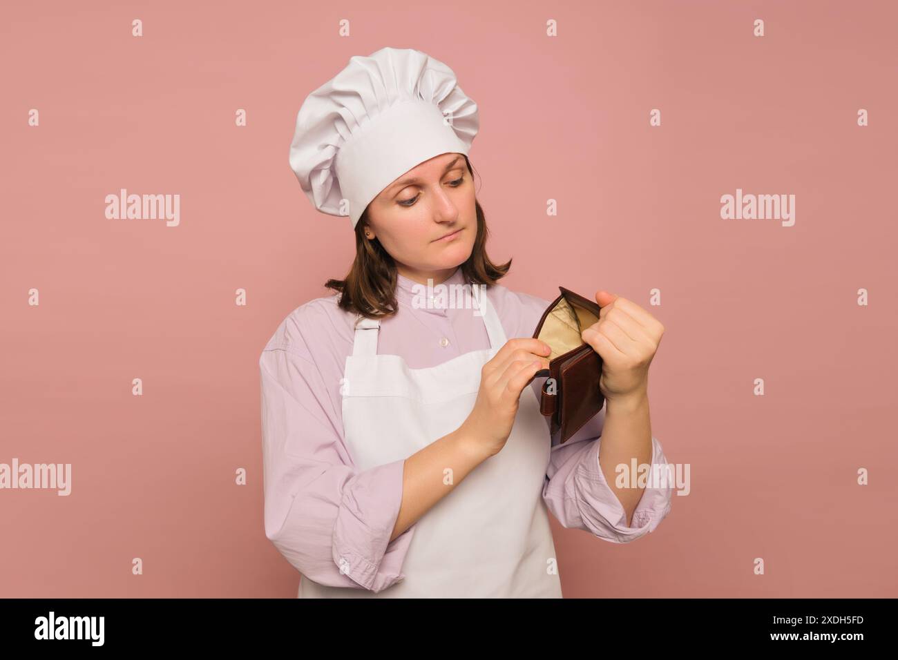 Woman cook with empty wallet on studio pink background. Portrait of a ...