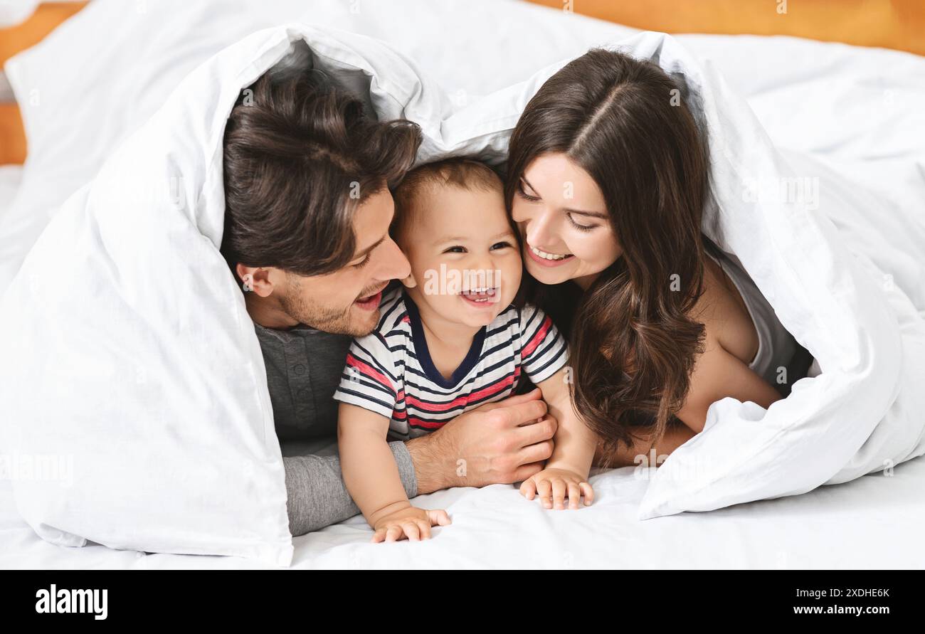 Happy Family Cuddling In Bed Together During The Day Stock Photo - Alamy