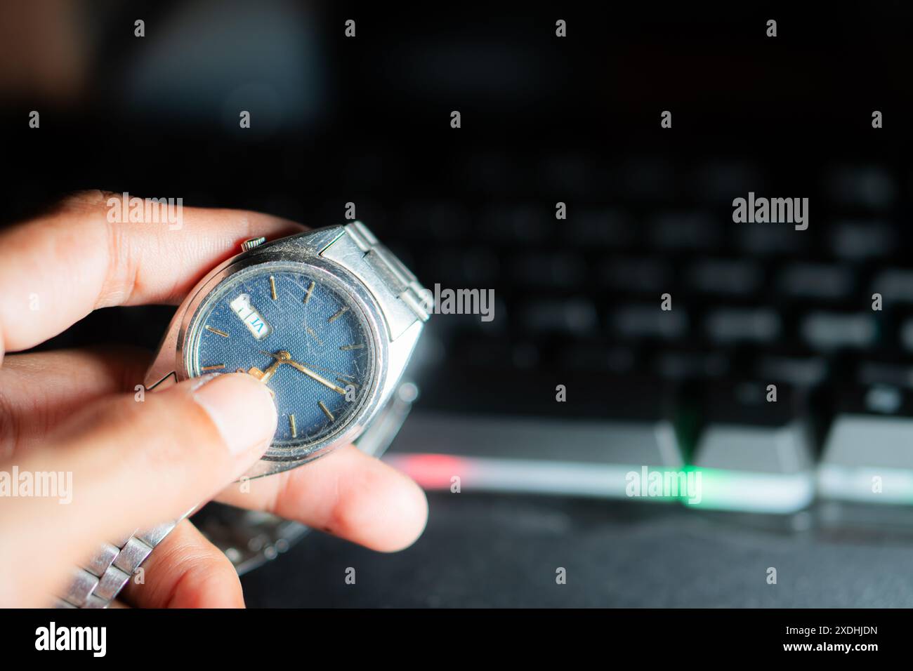 A close-up of a person adjusting the time on a wristwatch with a blue ...
