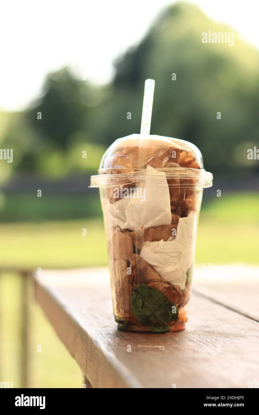 Plastic disposable cup with trash inside, close-up. Improper disposal ...