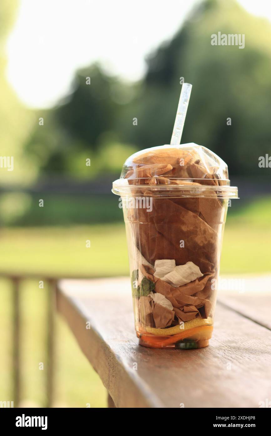 Plastic disposable cup with trash inside, close-up. Improper disposal ...