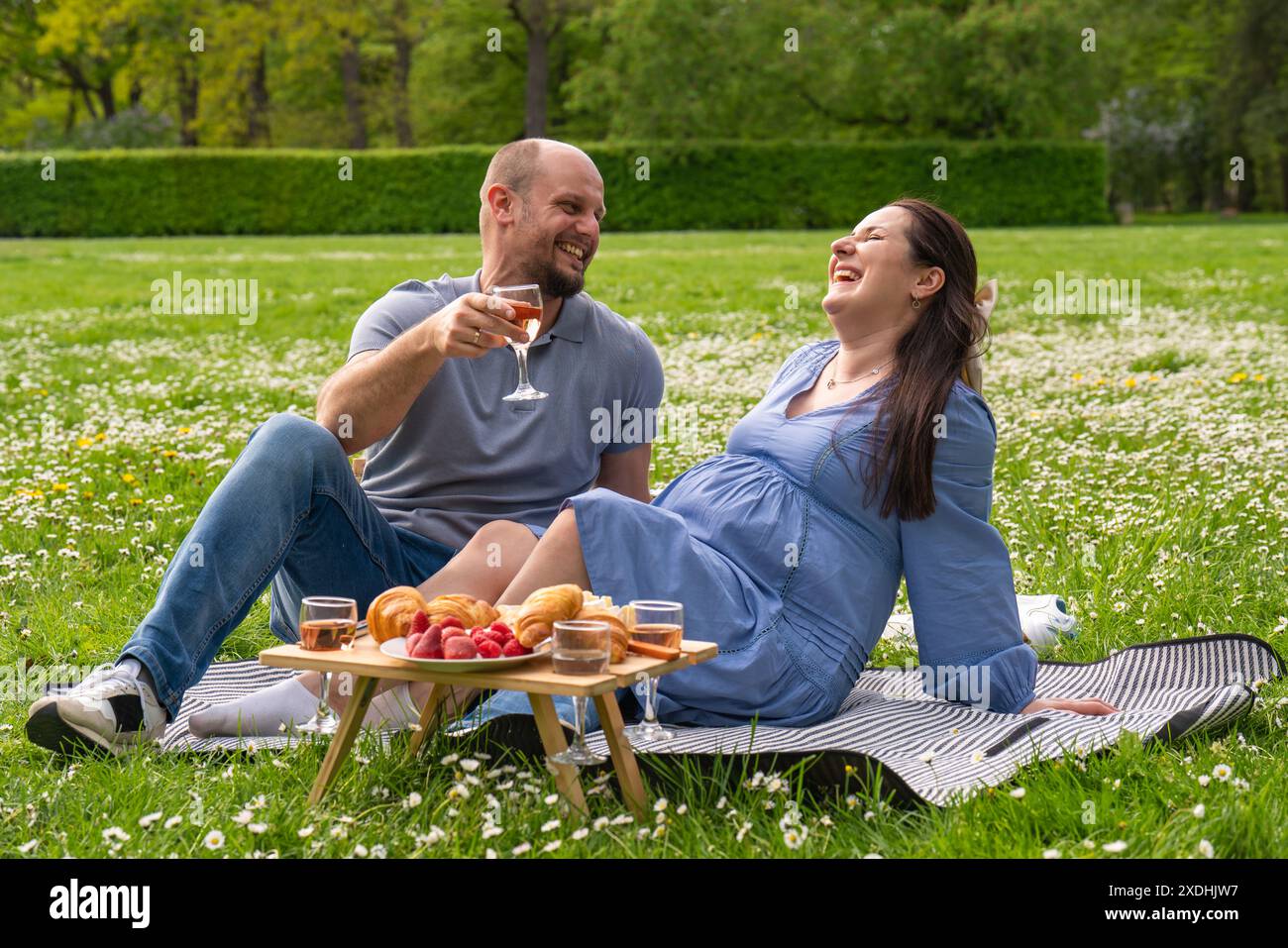 Happy pregnant couple spending time together on a picnic outdoors. They ...