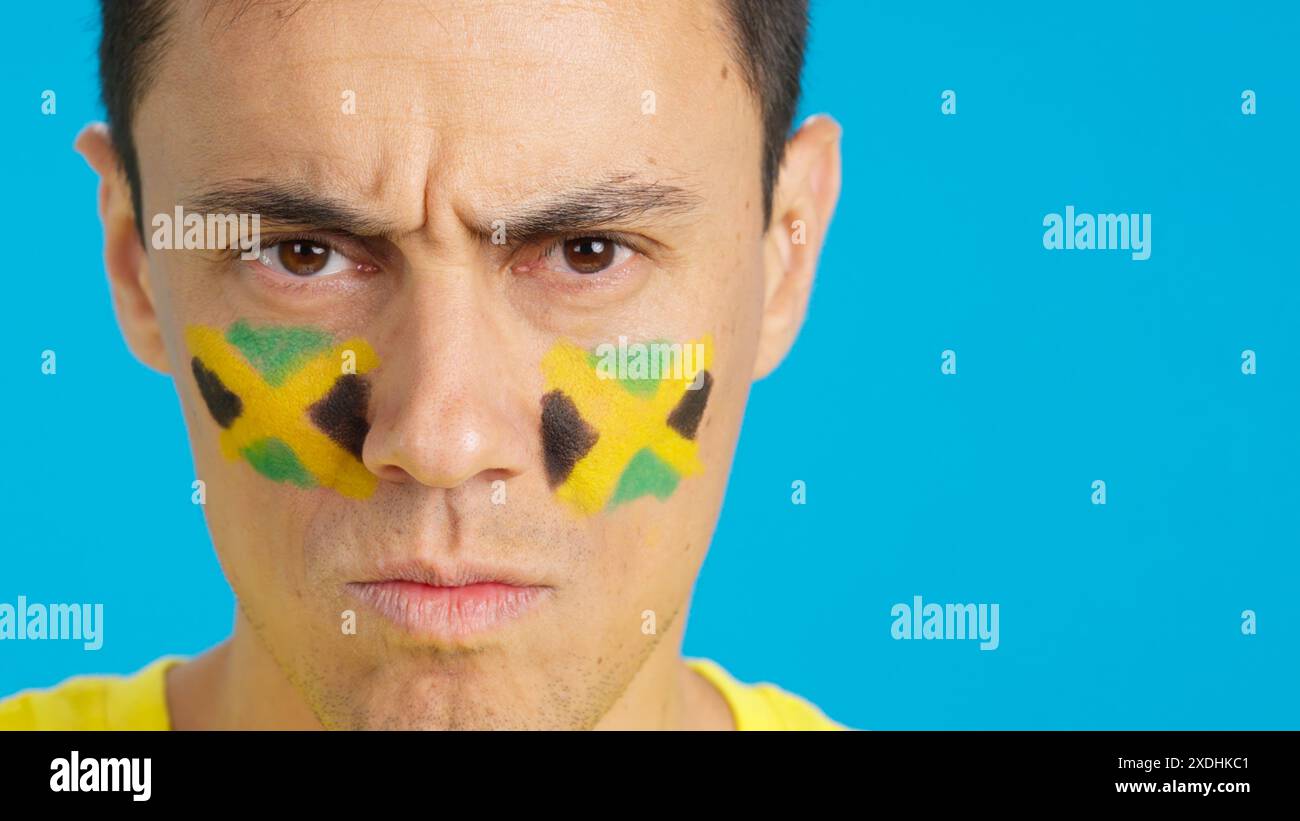 Serious man with a jamaican flag painted on the face Stock Photo - Alamy