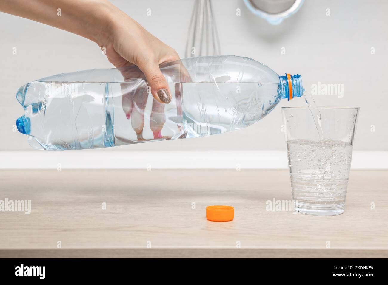 woman pours clean water into a glass from a plastic bottle. man pours ...