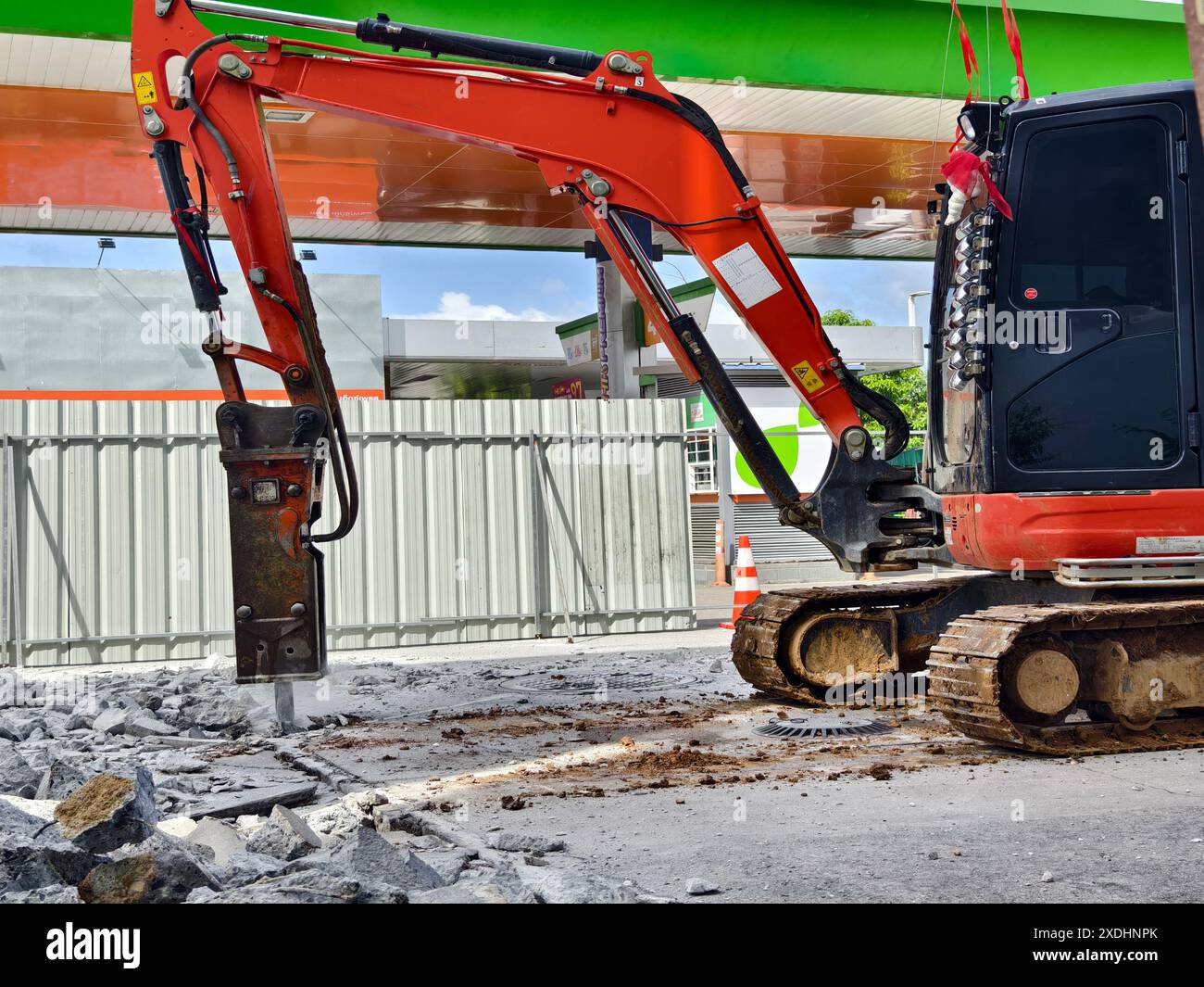Excavator using hydraulic hammer for breaking concrete at a ...